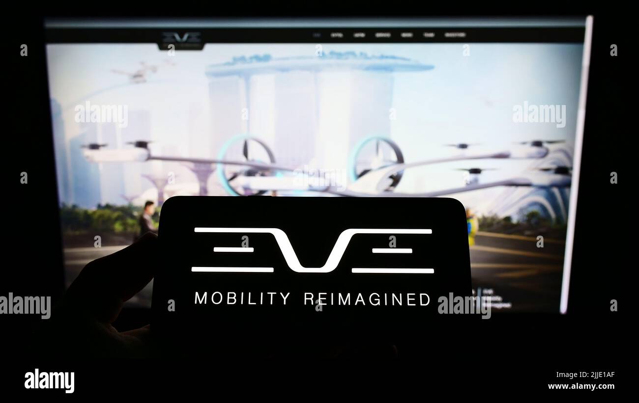 Person holding mobile phone with logo of company Eve Holding Inc. (Eve ...