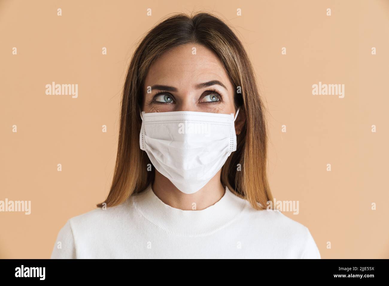 White mid woman looking at camera while posing in face mask isolated ...