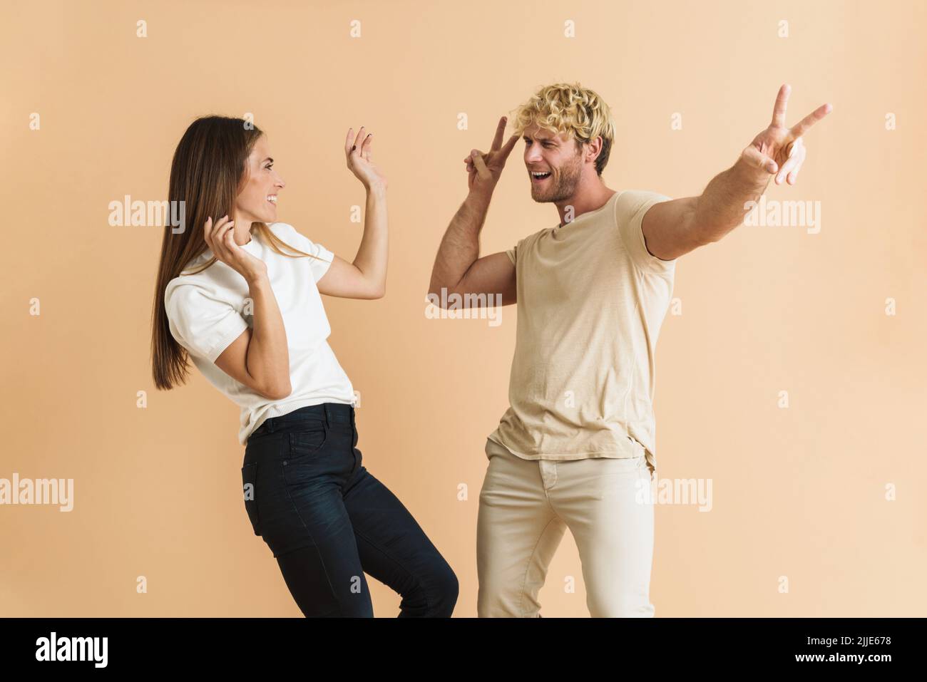 White couple gesturing and singing while dancing together isolated over ...