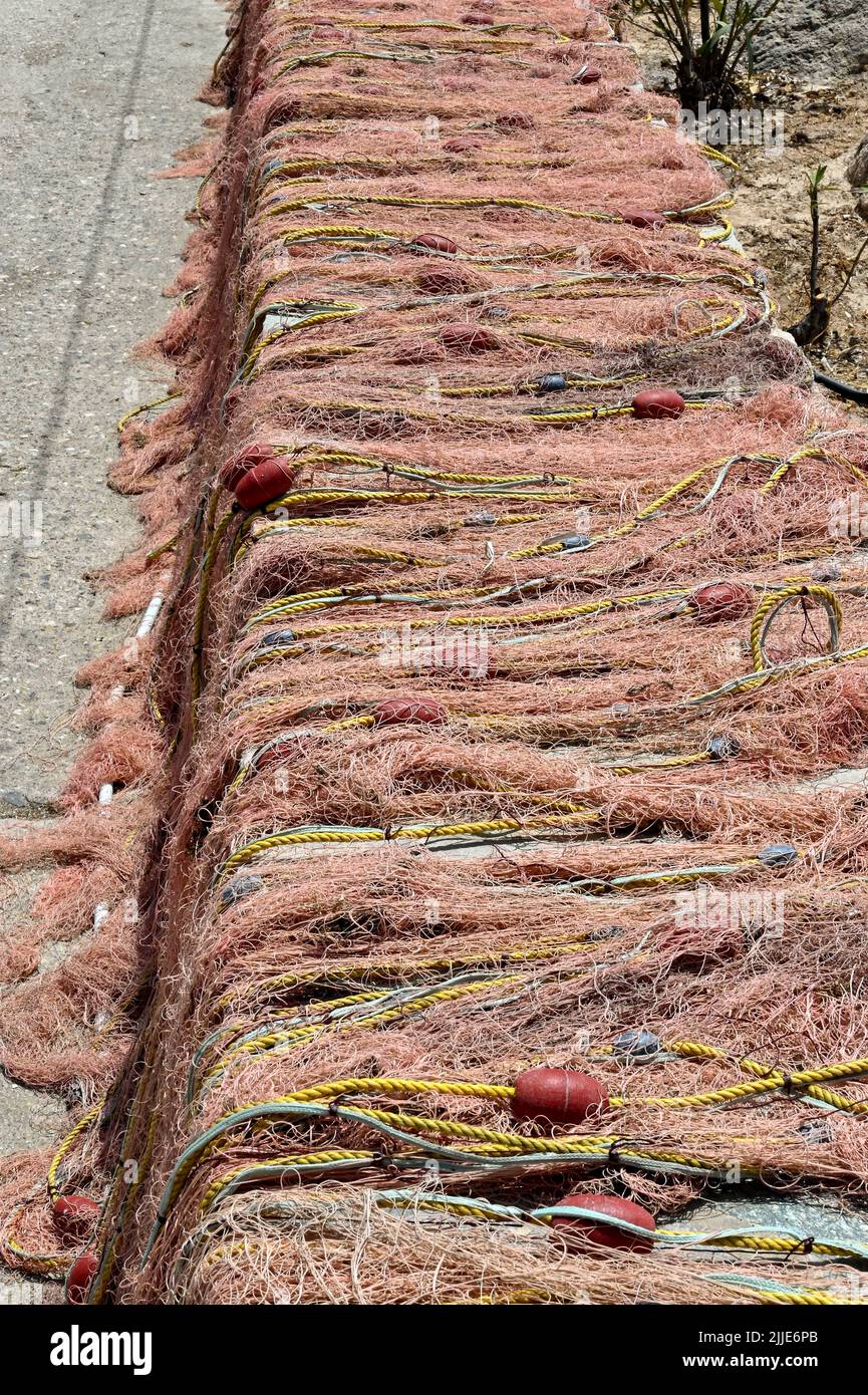 Fishing nets laid out on the harbour wall to dry out in the summer sun ...