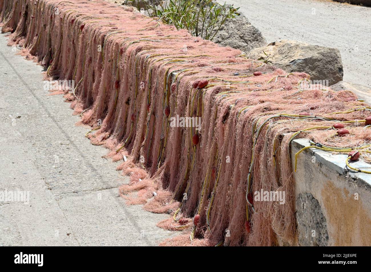 Fishing nets laid out on the harbour wall to dry out in the summer sun ...