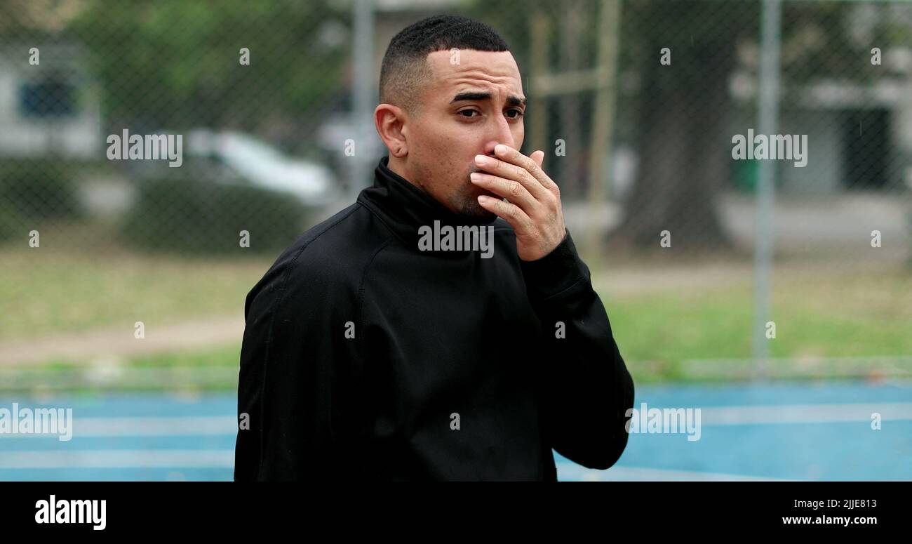 Hispanic man touching face and nose outside, walking towards camera ...