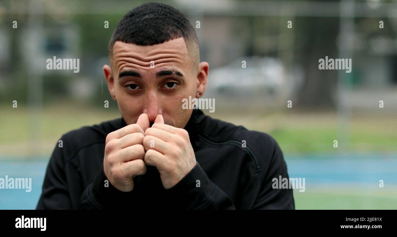 Hispanic man touching face and nose outside, walking towards camera ...
