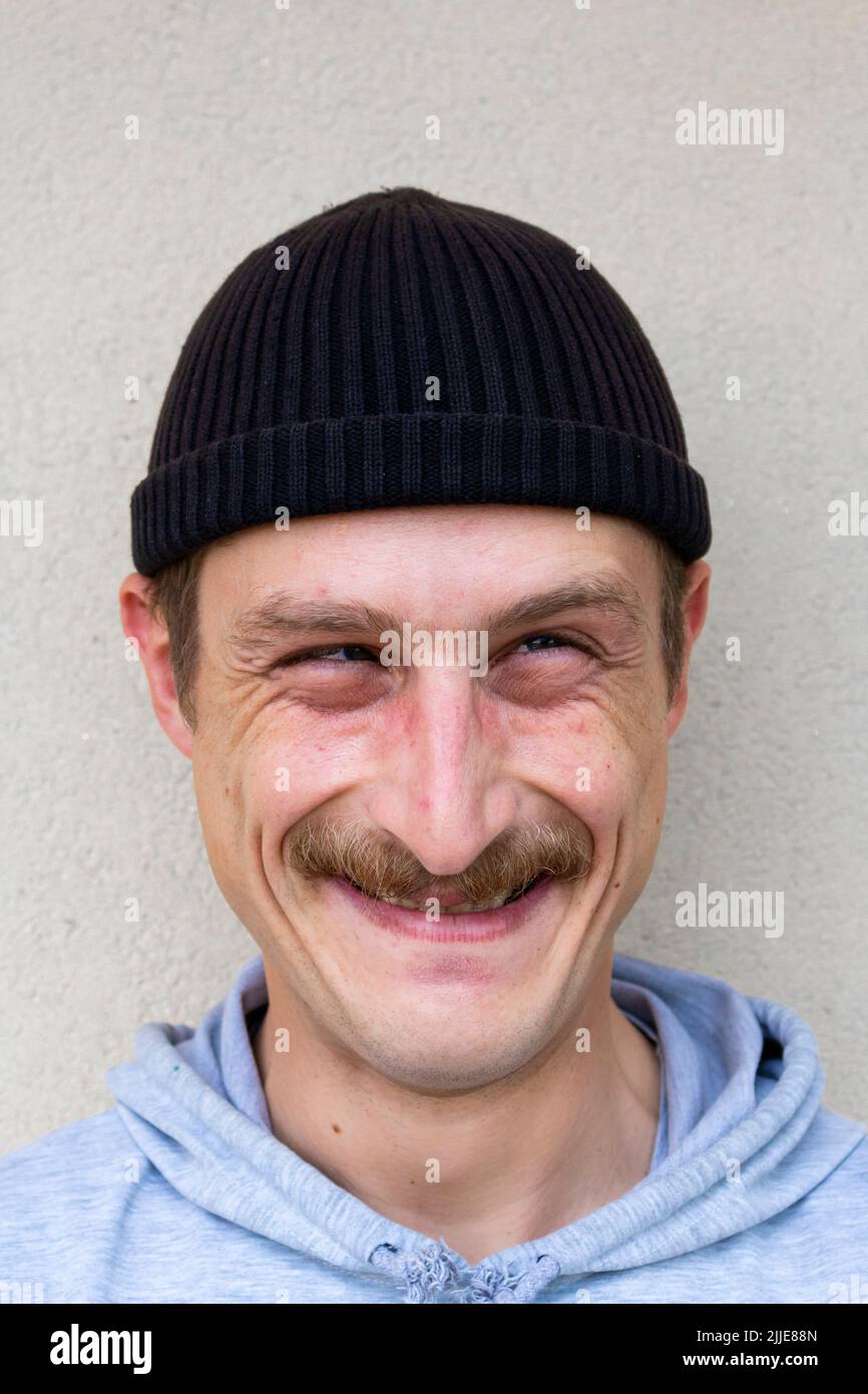 Portrait of young funny, crazy man with squinting eyes isolated on gray ...