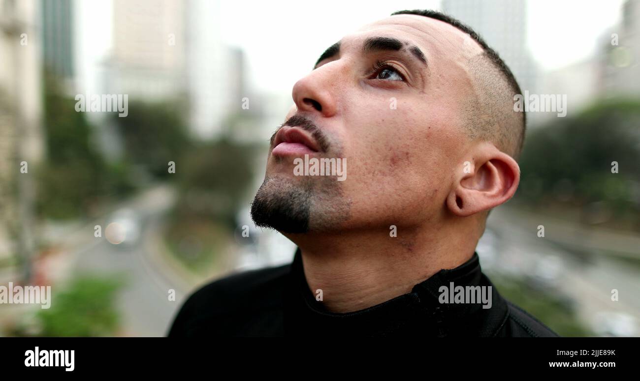 Hopeful Brazilian man looks at sky with faith closing and opening eyes ...