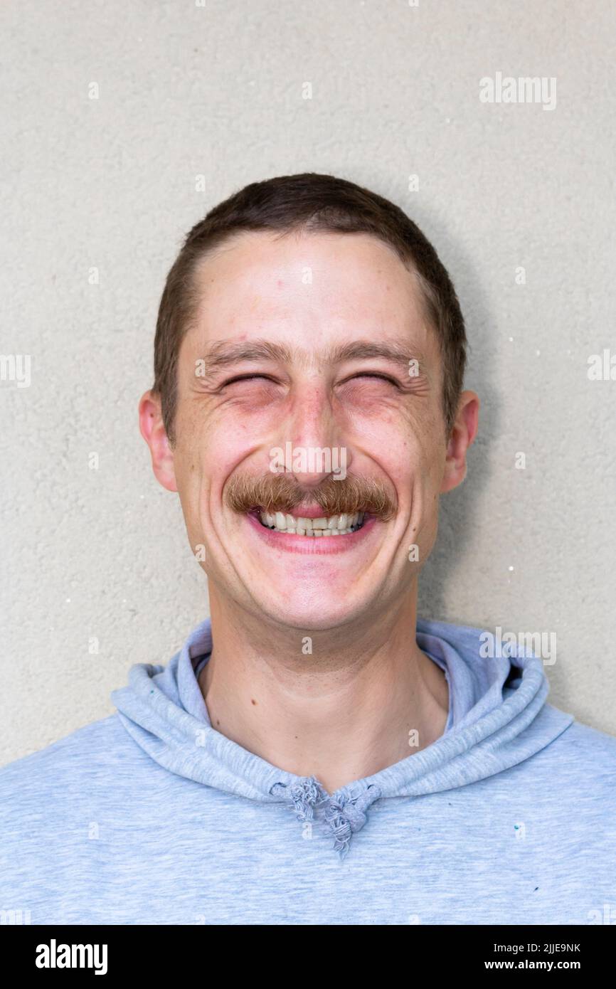 Portrait of young smiling, cheerful and crazy man with squinting eyes ...