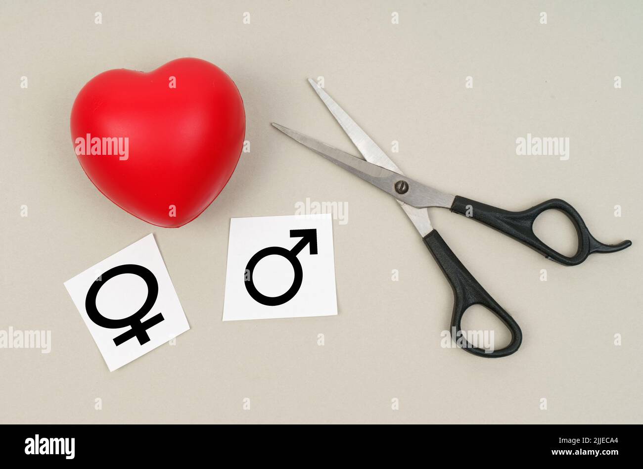 On a gray surface lies a heart, scissors and a sheet of paper with the ...