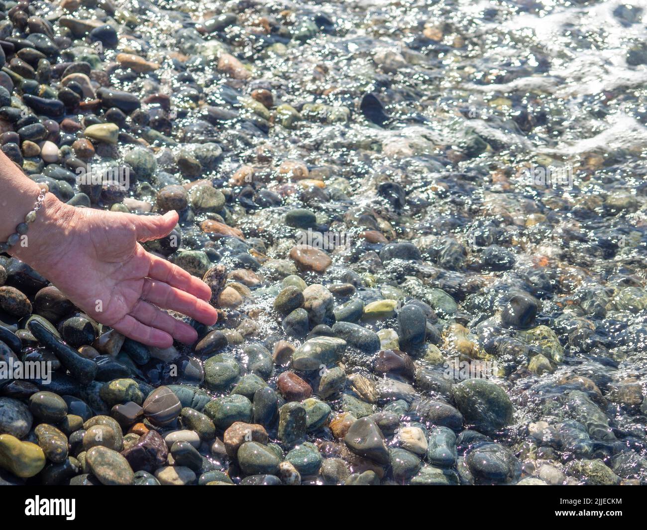 The hand reaches for the water. Sea wave and female hand. Feel the wave ...