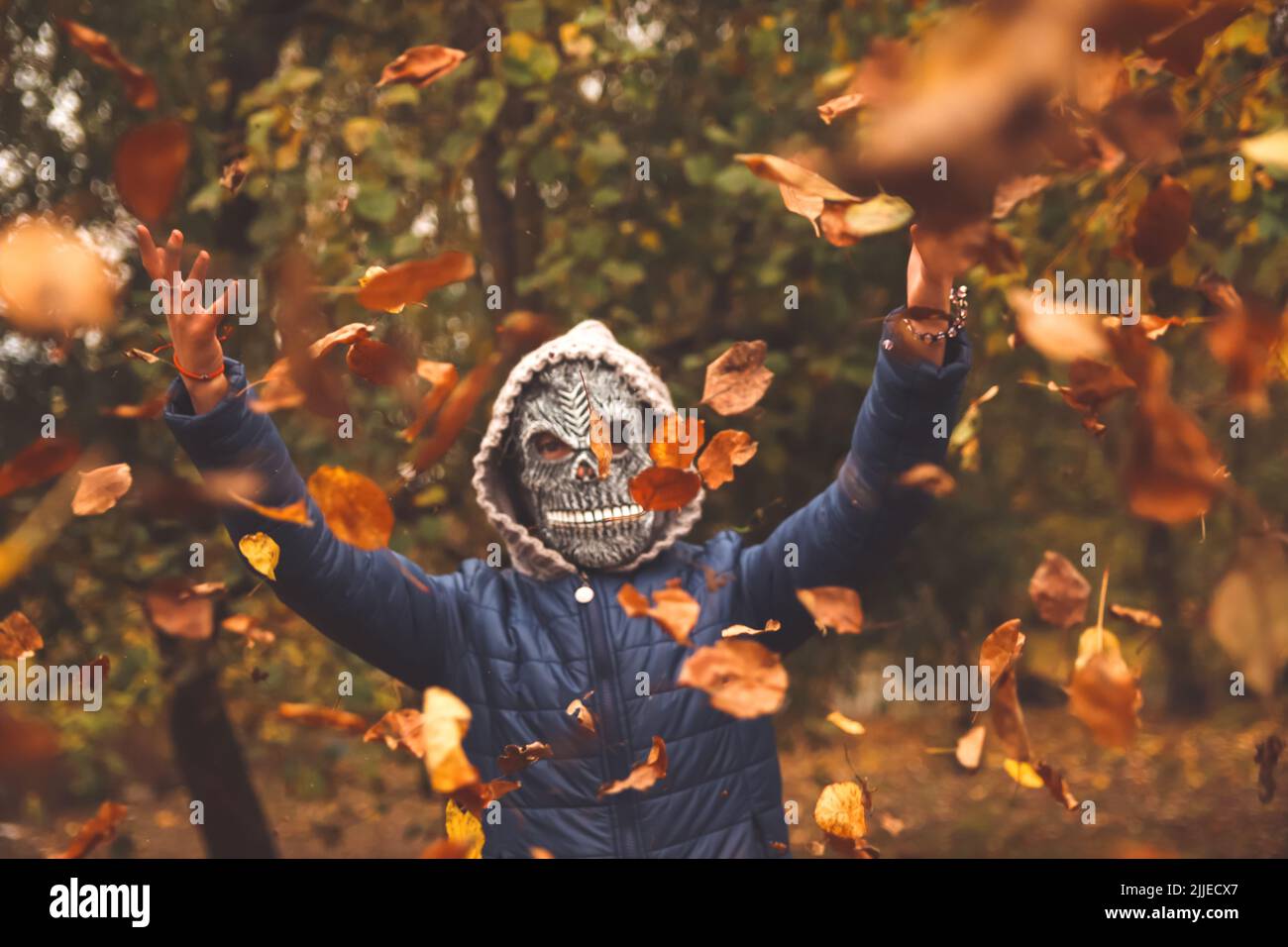 Defocus Halloween people. Person in grim reaper mask raising hand and ...