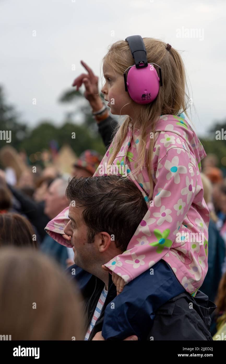 young girl with ear defenders on dads shoulders inFestival crowd at ...