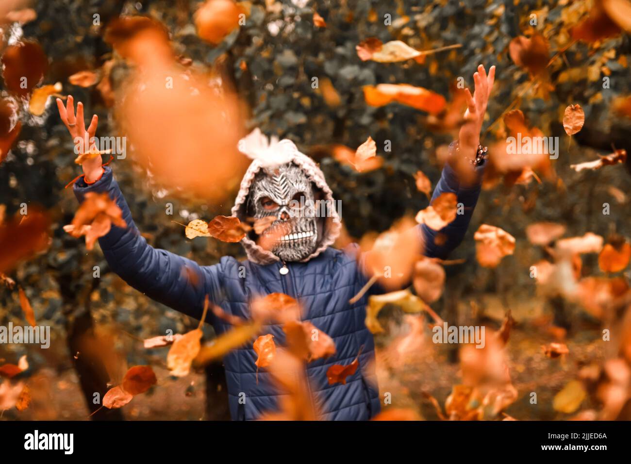 Defocus Halloween people. Person in grim reaper mask raising hand and ...