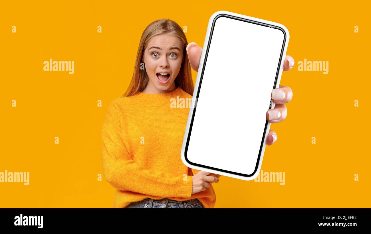 Emotional blonde lady showing mobile phone with blank screen Stock ...