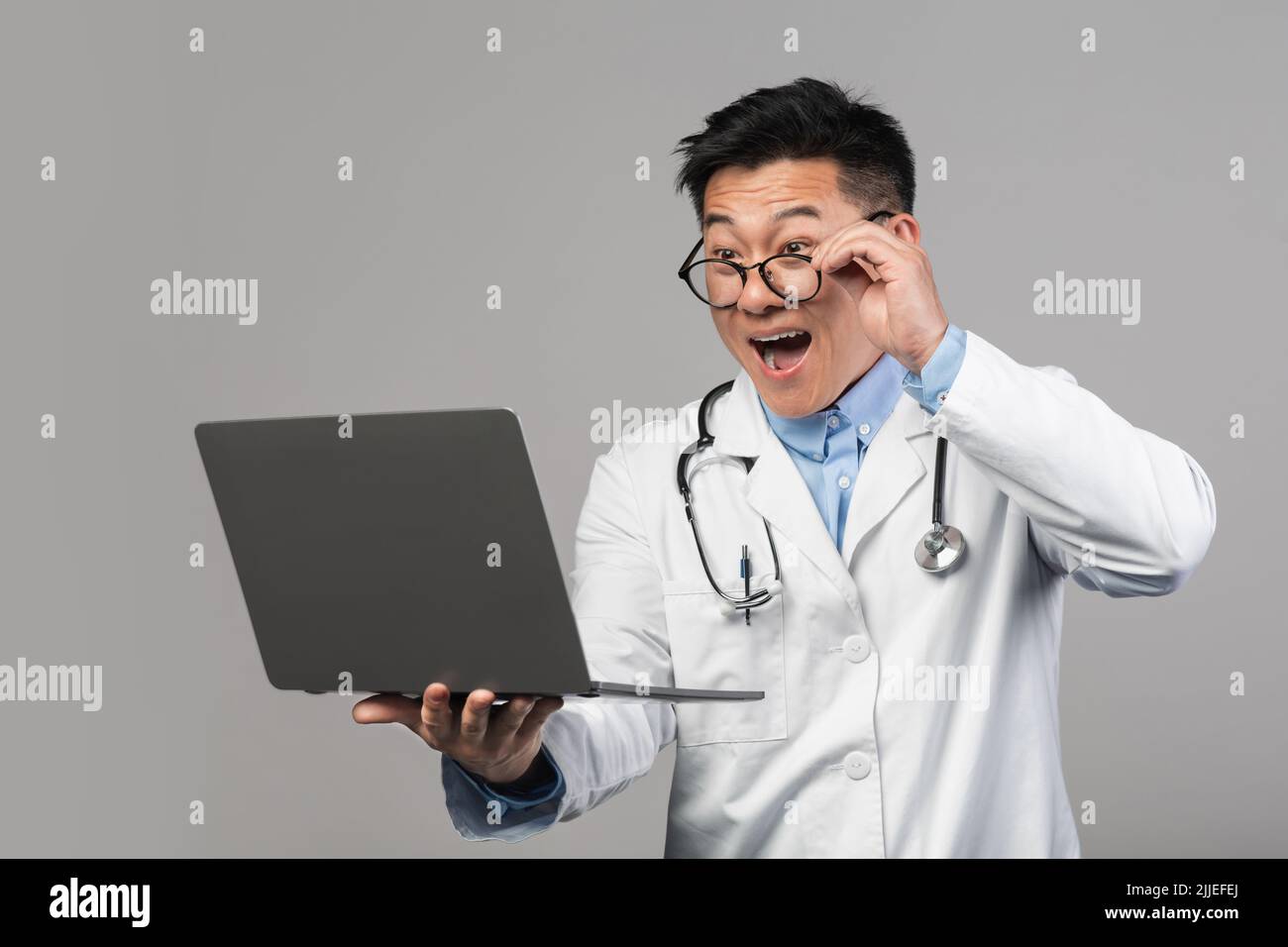 Shocked Cheerful Millennial Asian Man Doctor In White Coat With Open
