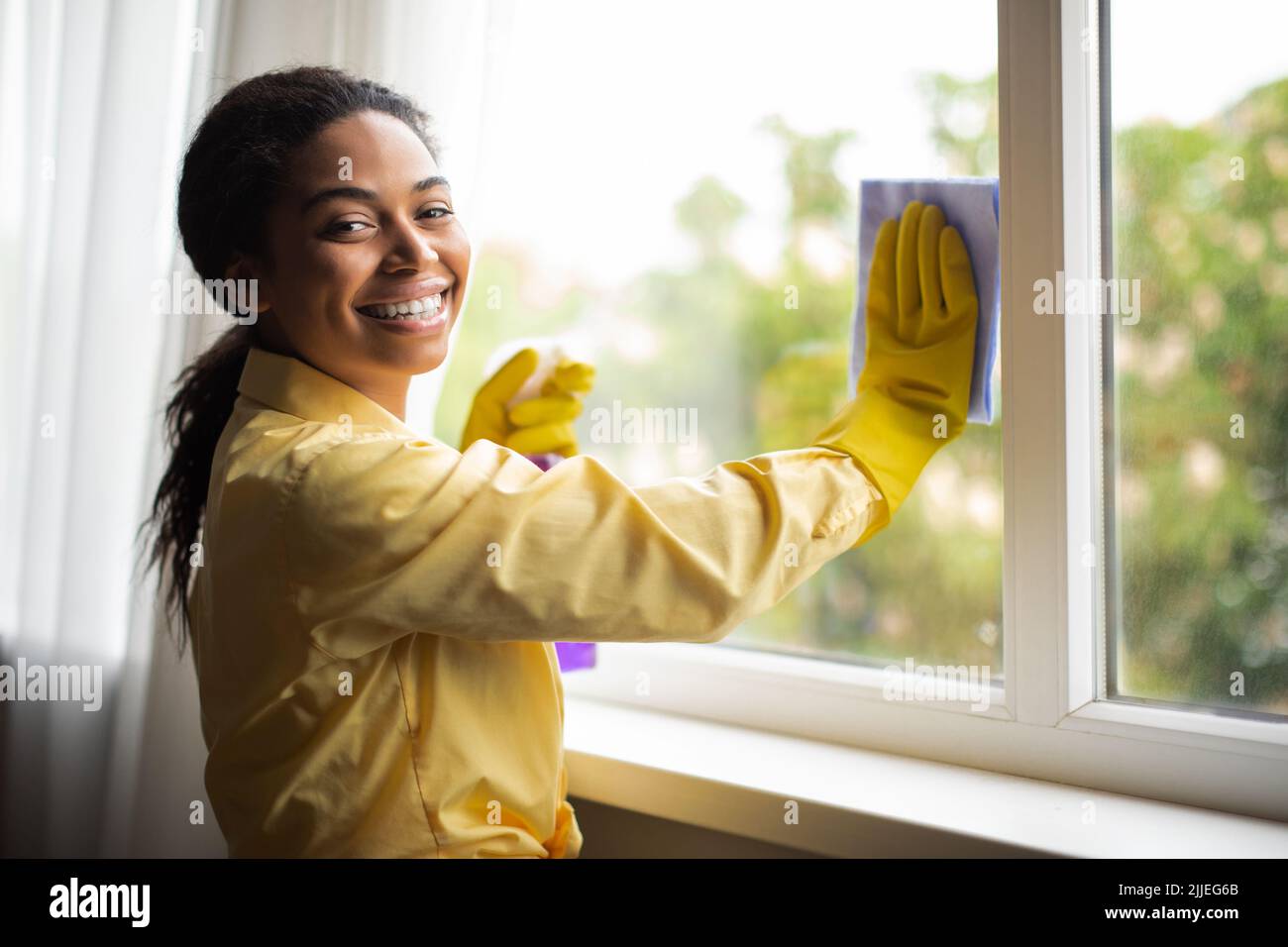 Black Woman Cleaning Window Glass Holding Rag And Detergent Indoors ...