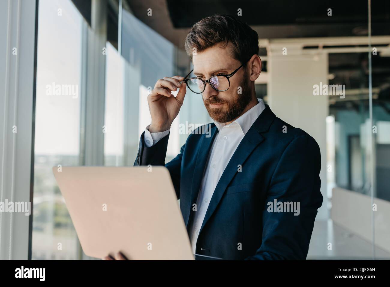 Focused businessman looking at laptop computer, working in modern ...