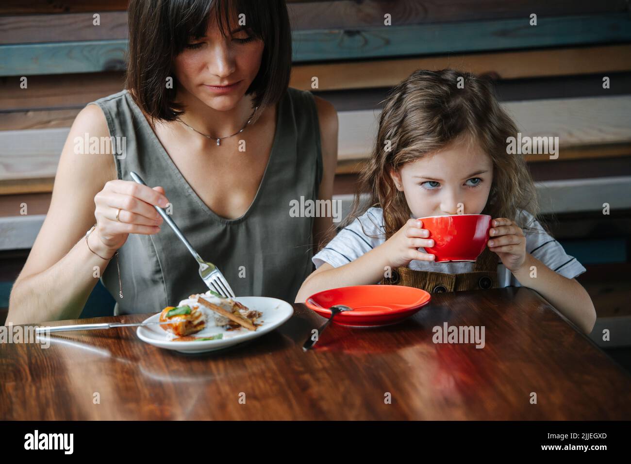 Mother is sitting in a cafe with her ten year old daughter, she is ...