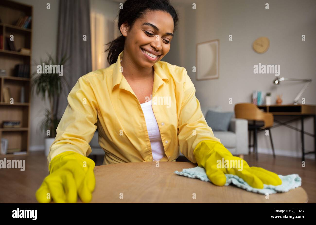 Cheerful African Female Dusting Table Cleaning Desktop With Rag Indoor ...
