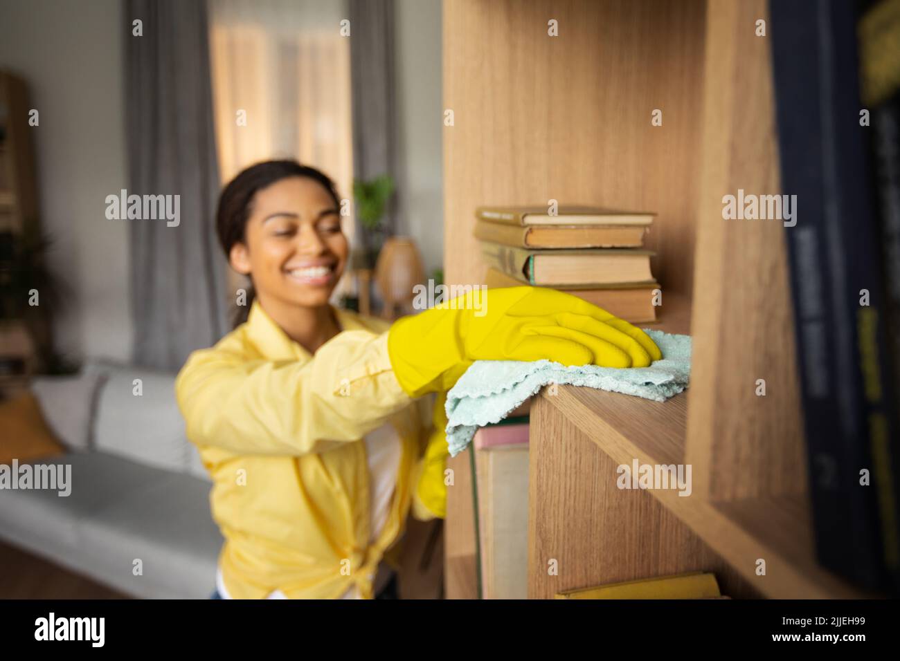 African Female Dusting Bookshelf With Rag Doing Housework At Home Stock ...