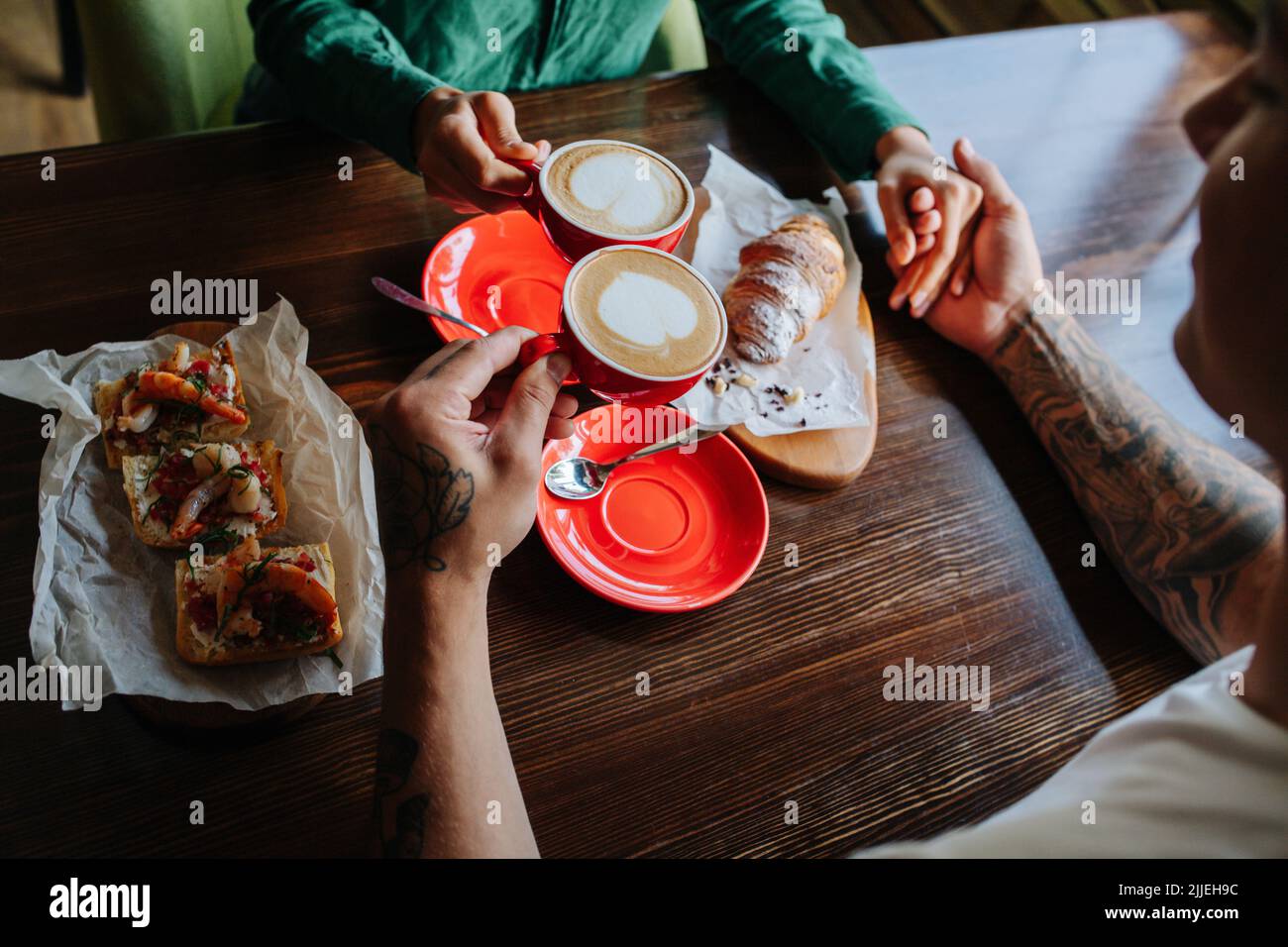 No face image of a couple sitting in a cafe opposite to each other ...