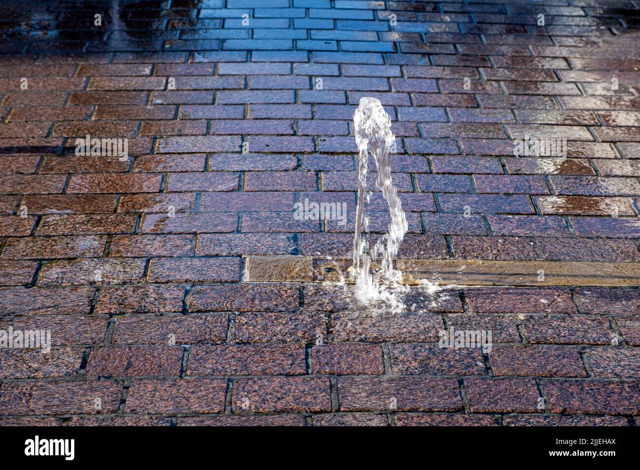 water fountain from a street of red cobblestones in sunlight Stock ...