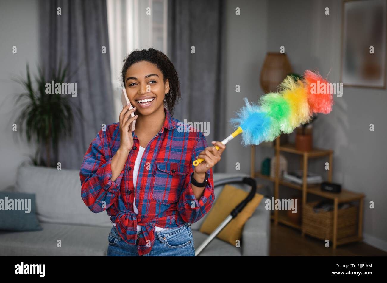 Smiling cheerful young african american female dusting with brush and ...