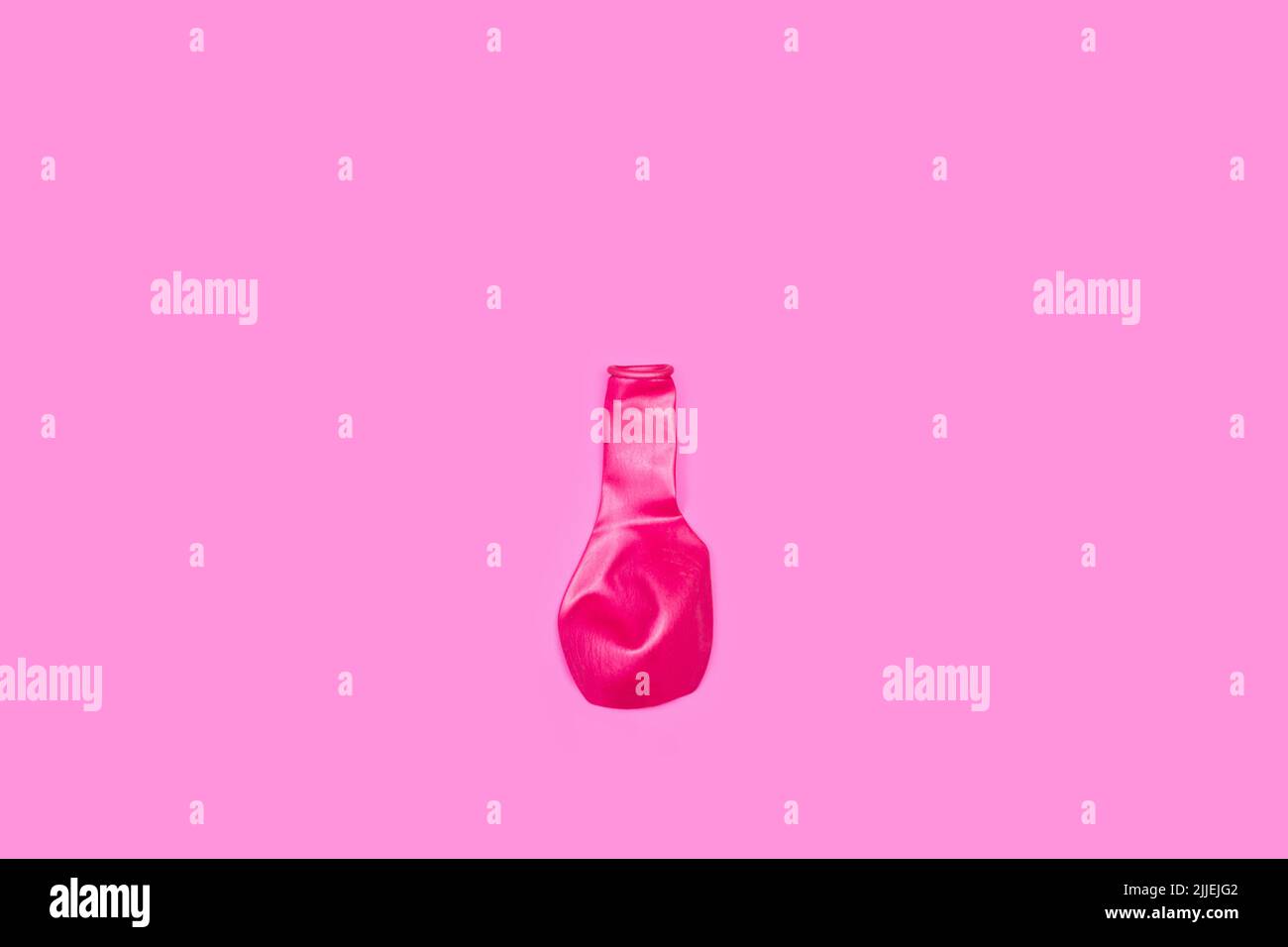 A deflated pink balloon on a pink background with copy space Stock ...