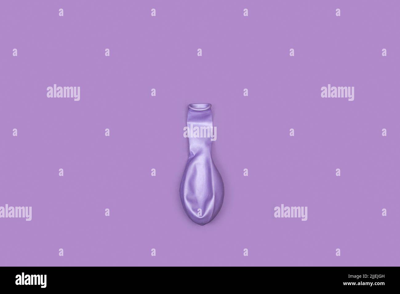 A deflated purple balloon on a purple background with copy space Stock ...
