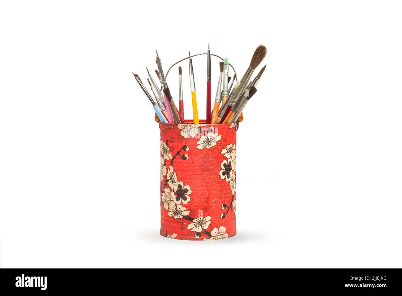 Artistic paintbrushes in a colored tin can on a white background with ...