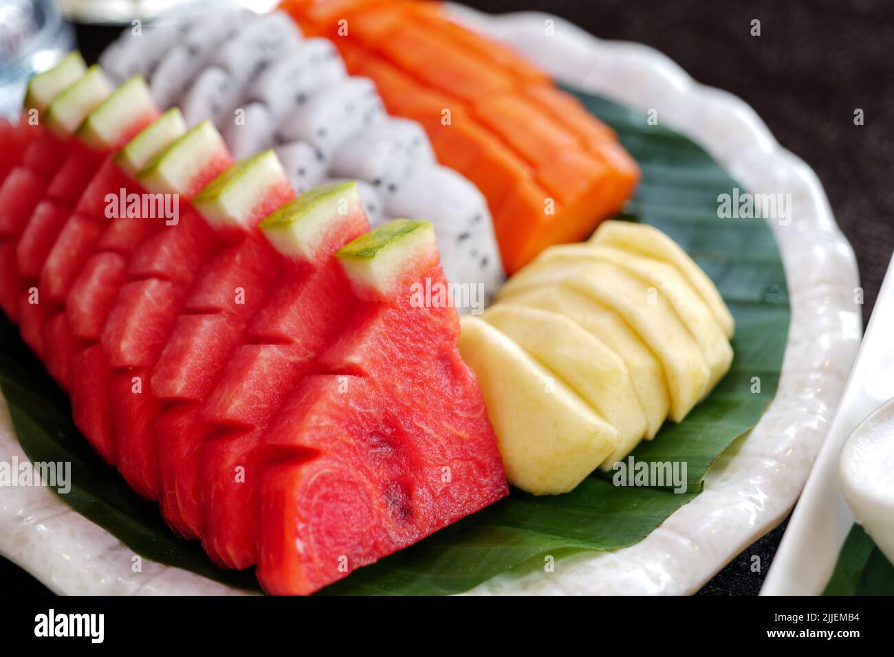 Mix various slice of tropical fruit on banana leaf and white plate ...