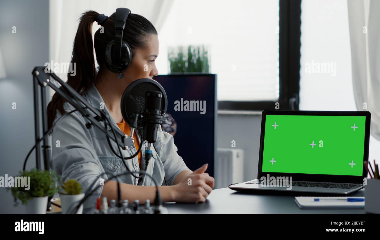 Influencer in studio presenting product on laptop with green screen ...