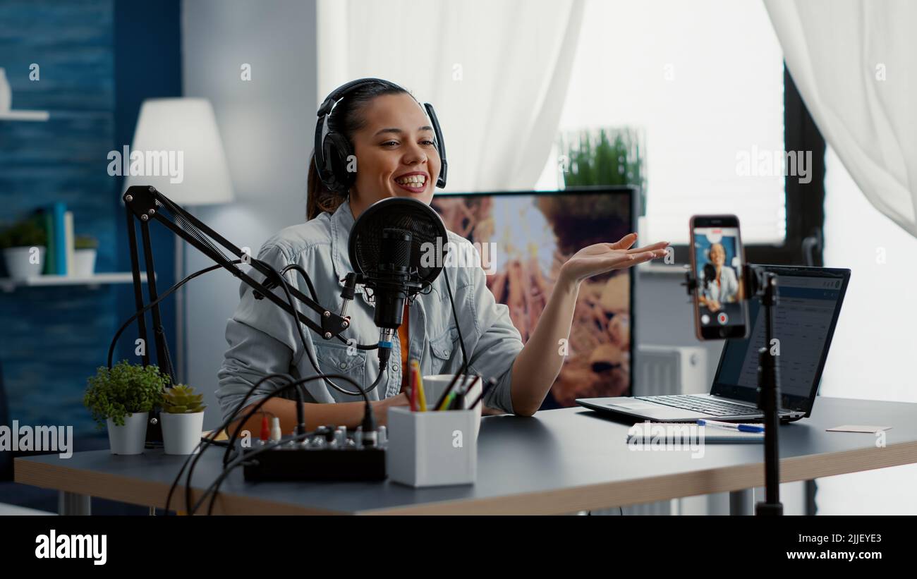 Influencer putting on headphones while recording video with phone and ...