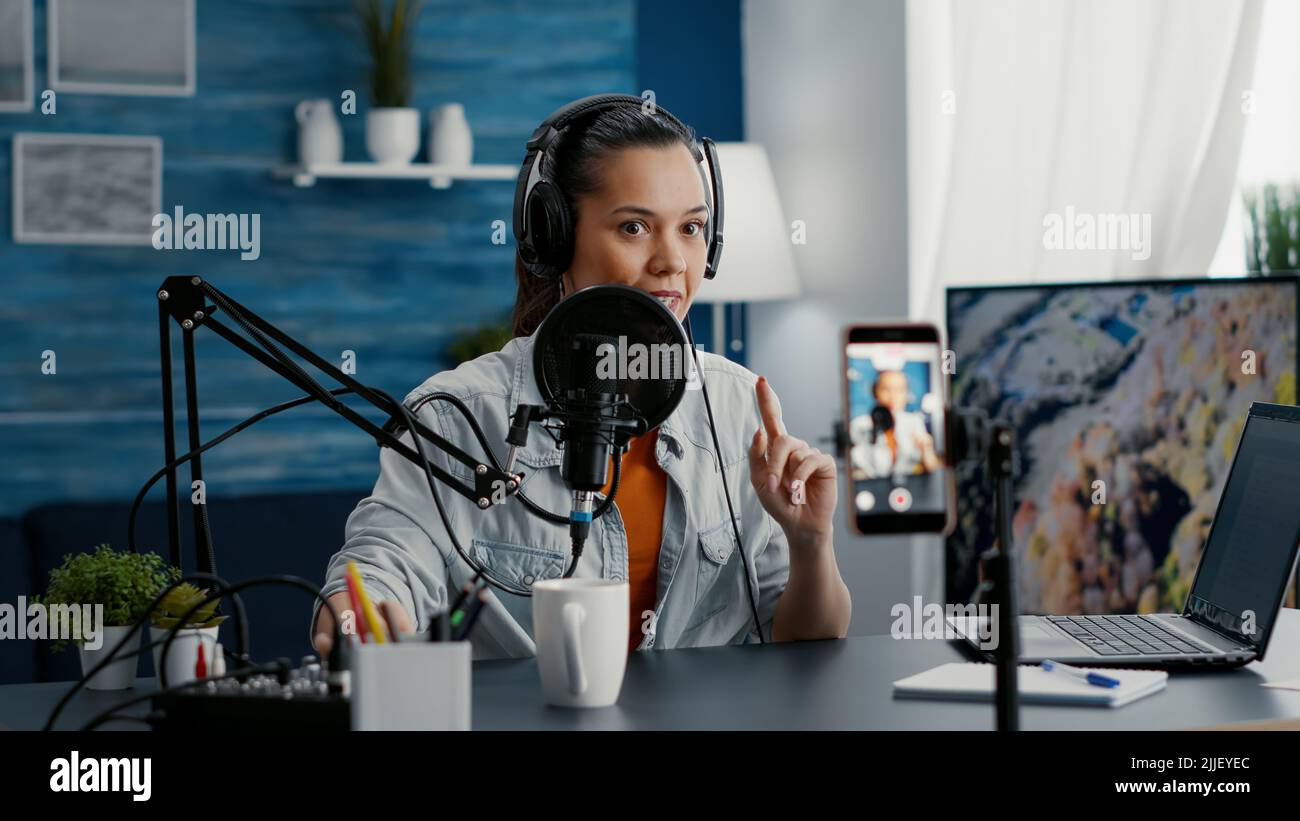 Excited famous vlogger recording video with smartphone while talking to ...