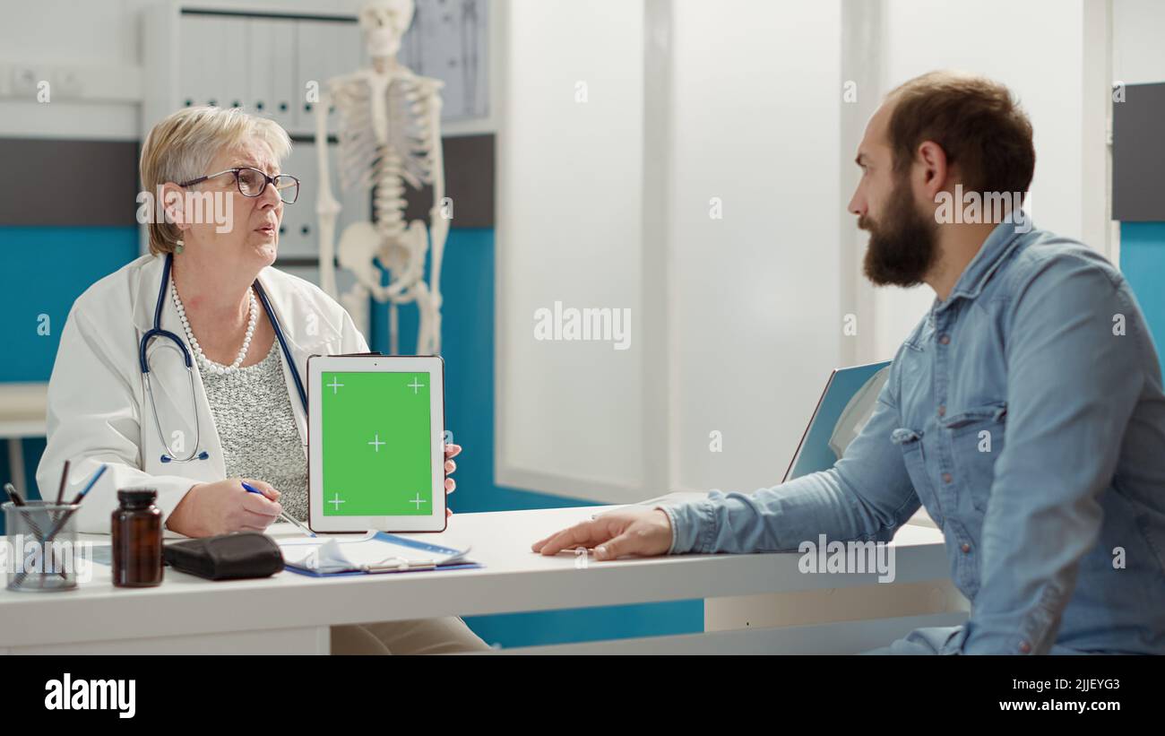 Doctor vertically holding greenscreen on digital tablet in cabinet ...
