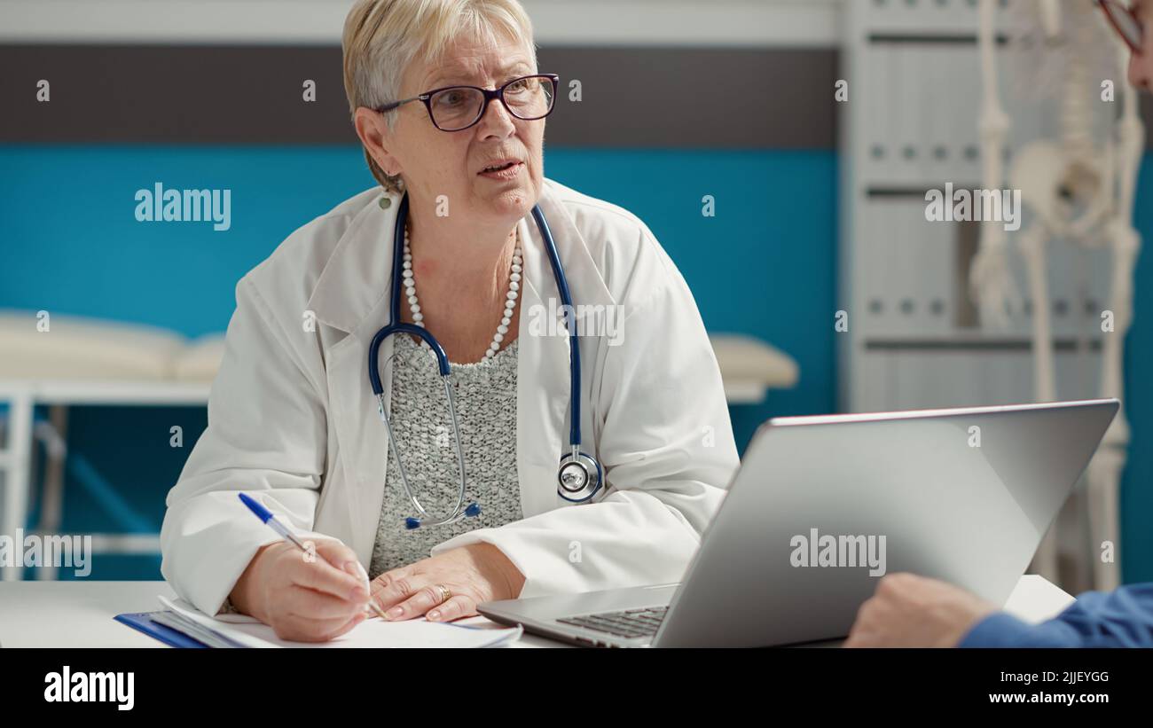 General practitioner taking checkup visit notes on documents, creating ...