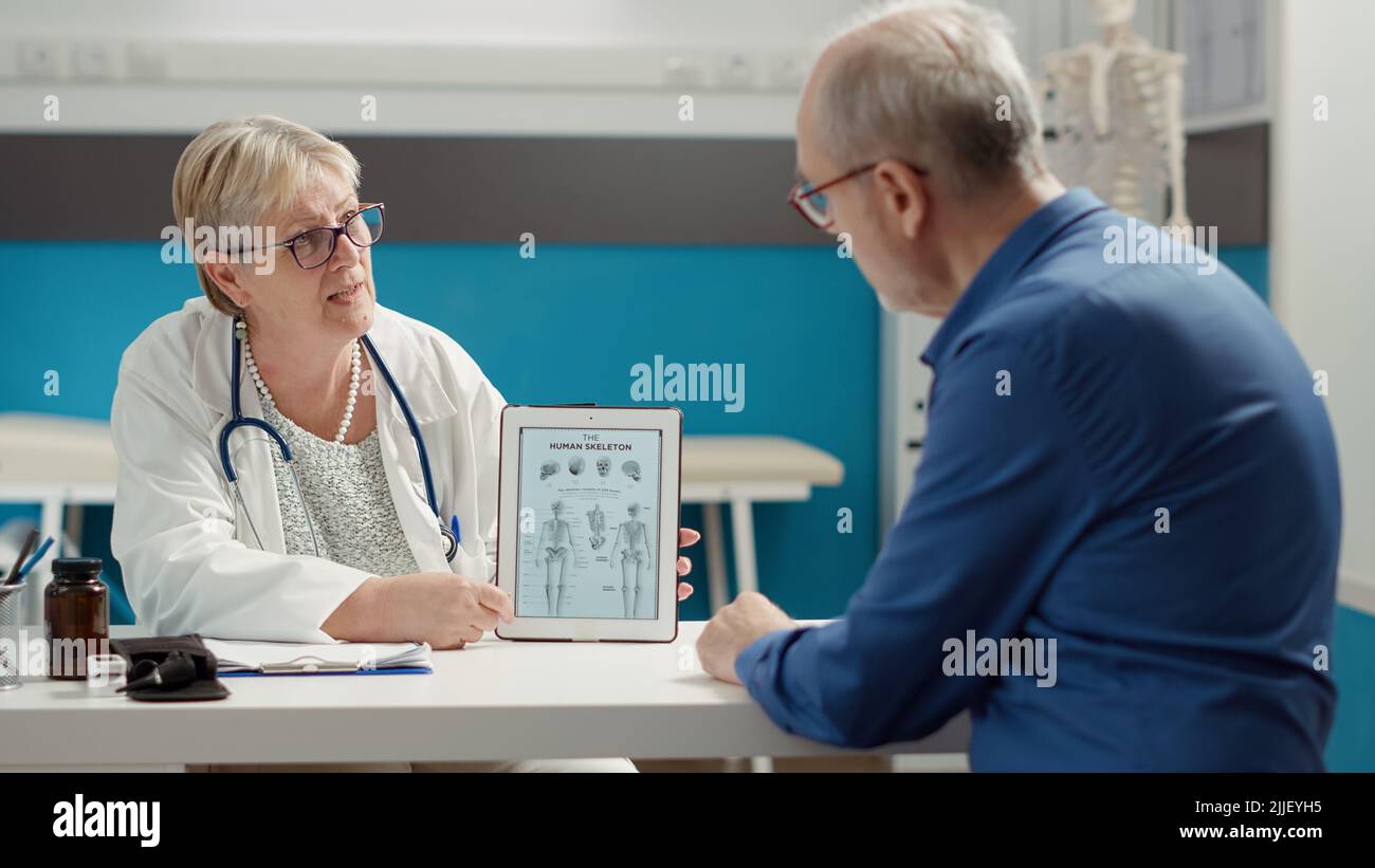 Medical specialist explaining human skeleton image on digital tablet ...