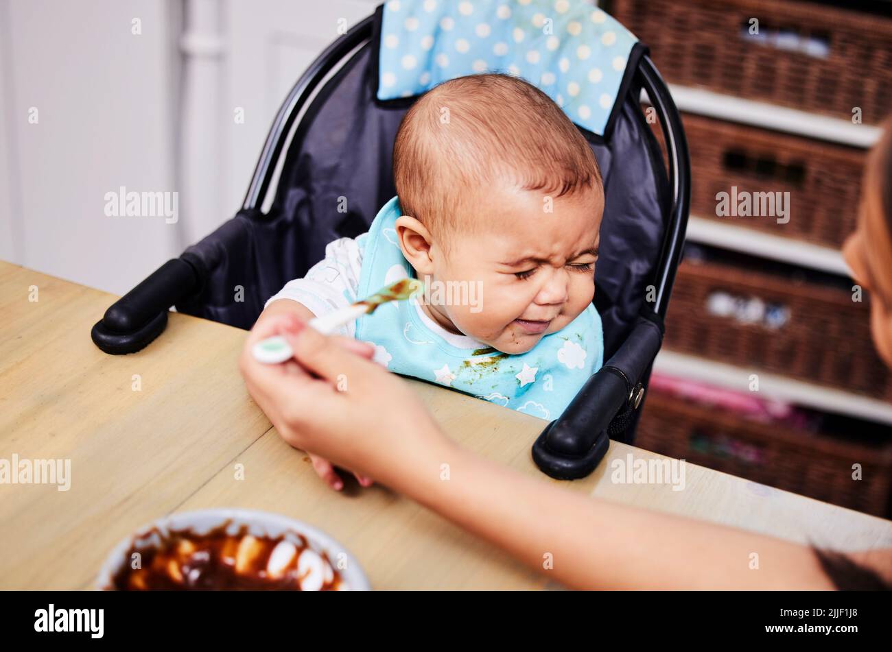 Should we try something else. a baby turning away while being fed by ...
