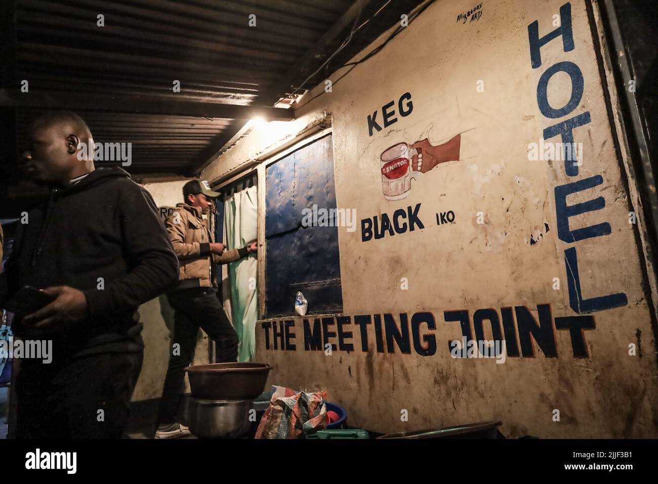Residents are seen outside a busy restaurant in Kibera Slum. Street ...