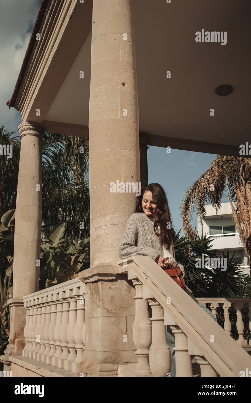 Woman stand near old building with columns and tropical plants in ...