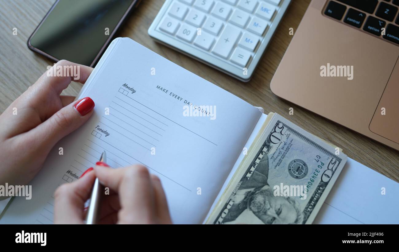 Female making notes in notepad and counting cash Stock Photo - Alamy