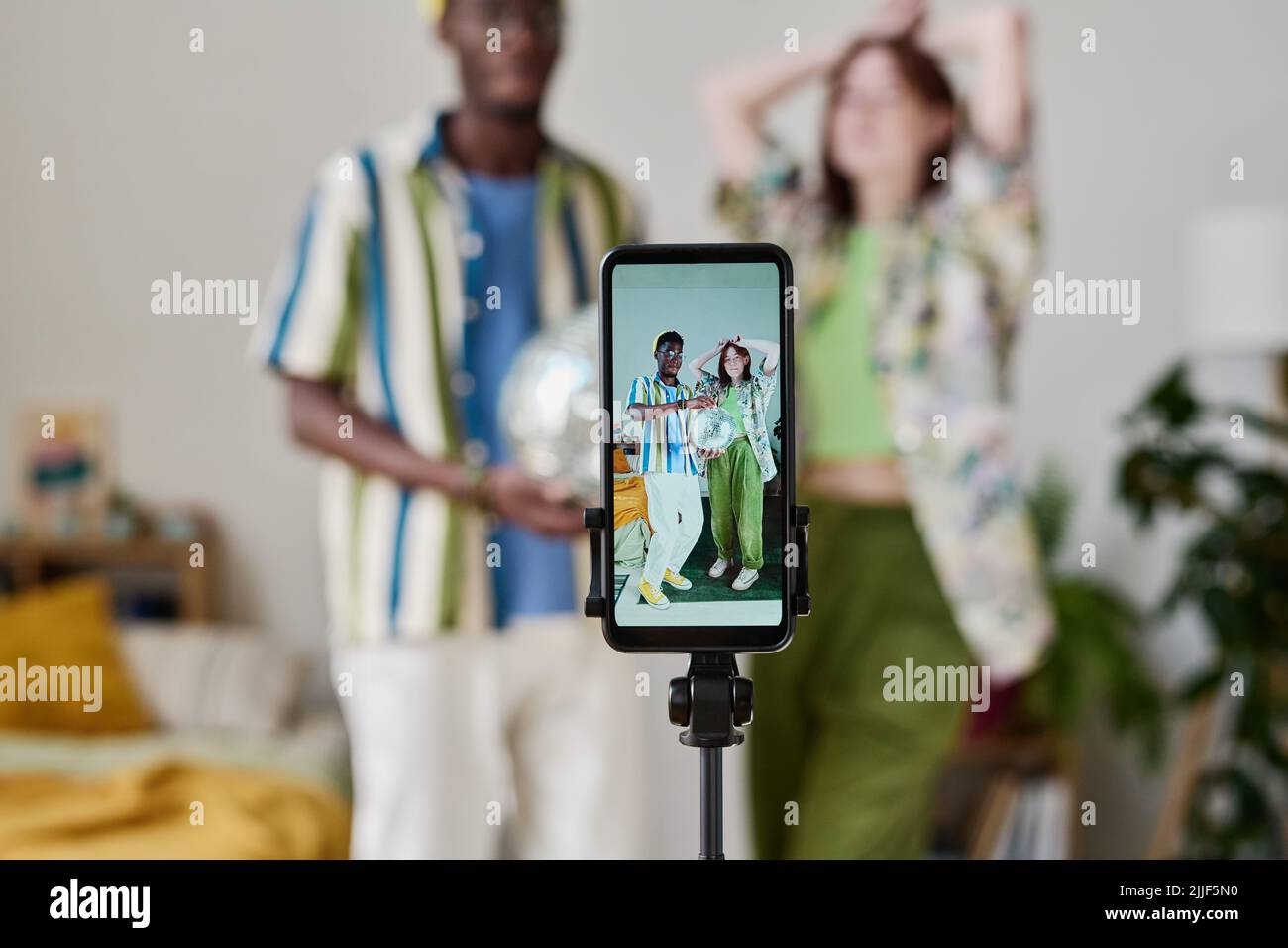 Close-up of couple of vloggers dancing together with disco ball and ...