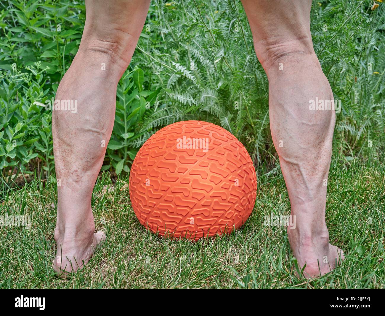 senior man legs and heavy rubber slam ball filled with sand in a ...