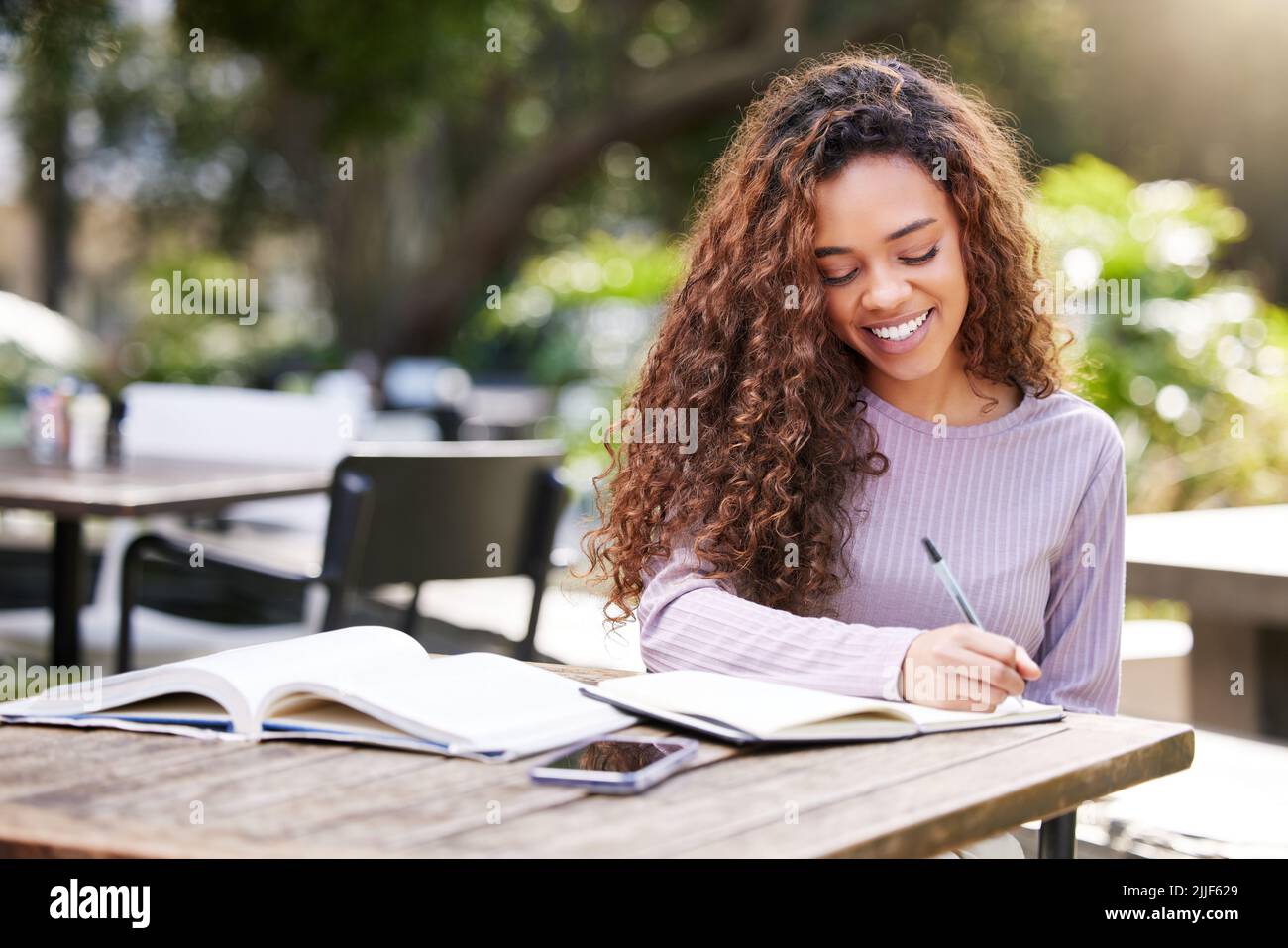 Taking notes helps me remember better. a young female student studying ...