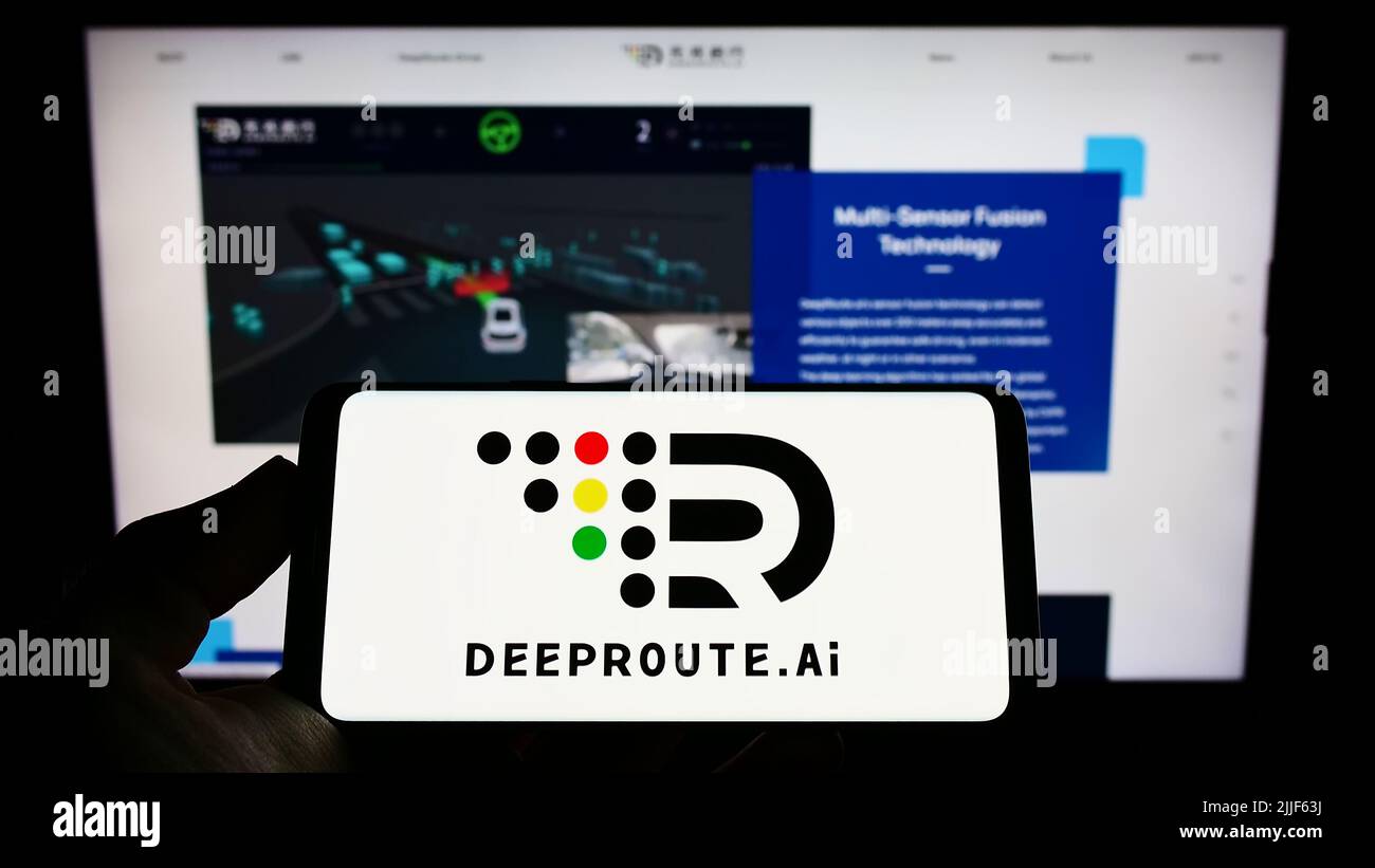 Person holding cellphone with logo of Chinese company Shenzhen Deeproute.ai Co. Ltd. on screen ...