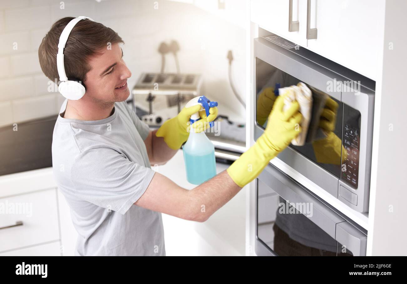 Music makes any activity better. a young man cleaning the kitchen at ...