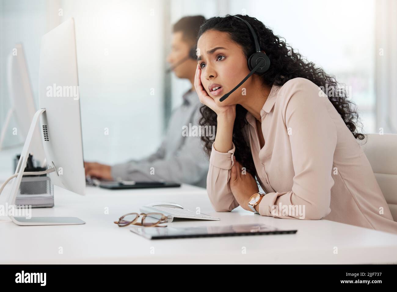 Stuck in a rut. a young call centre agent looking stressed out while ...