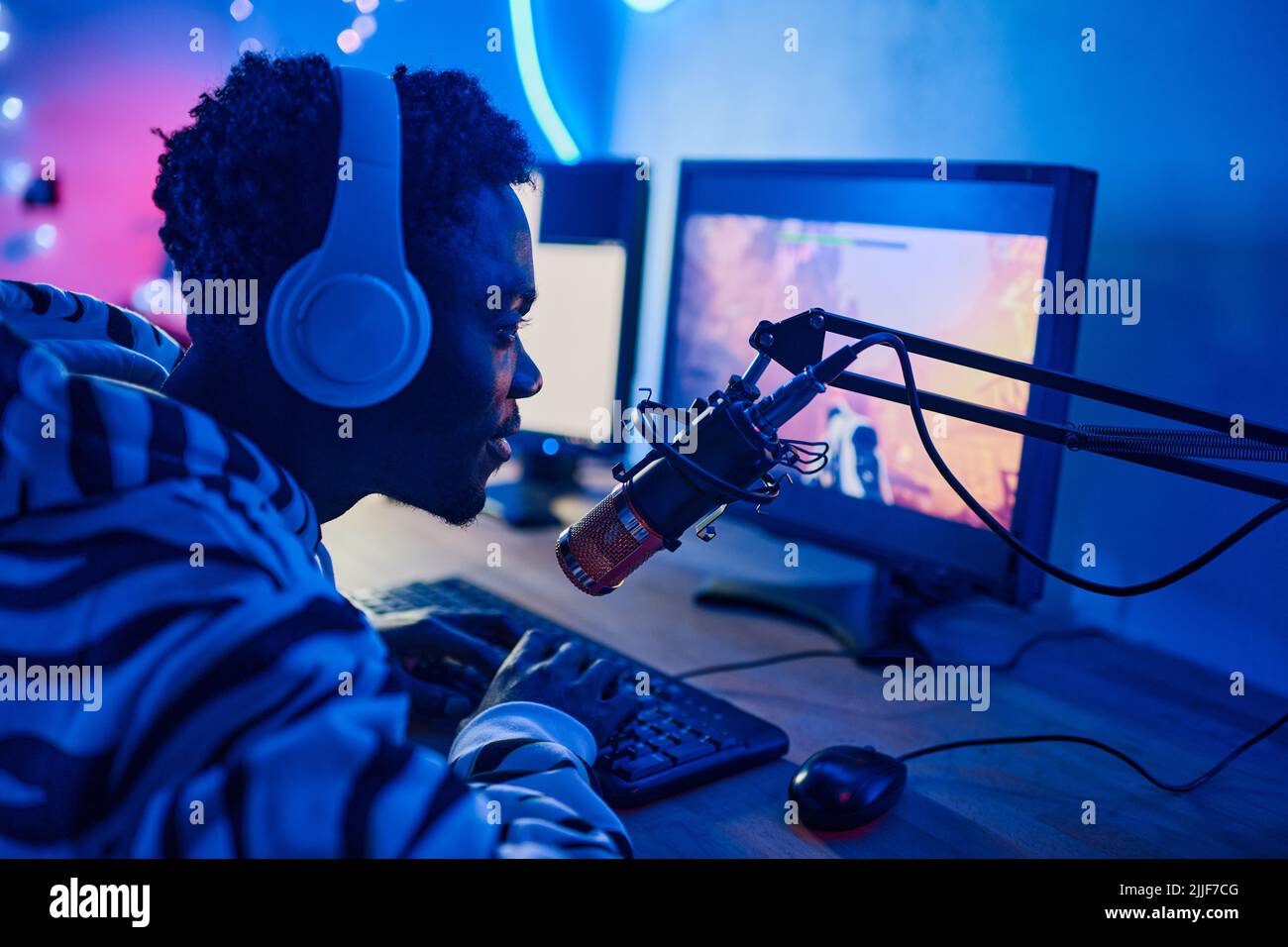 African teenage boy in headphones speaking in microphone while playing ...