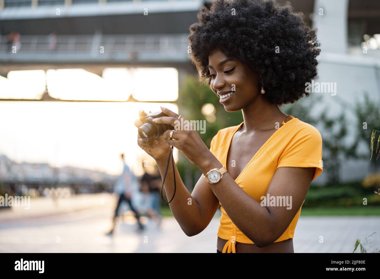 Smiling African american woman using professional camera at a street ...
