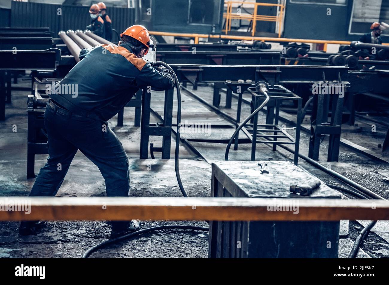 Worker at steel factory. Process of making steel pipes under hot ...