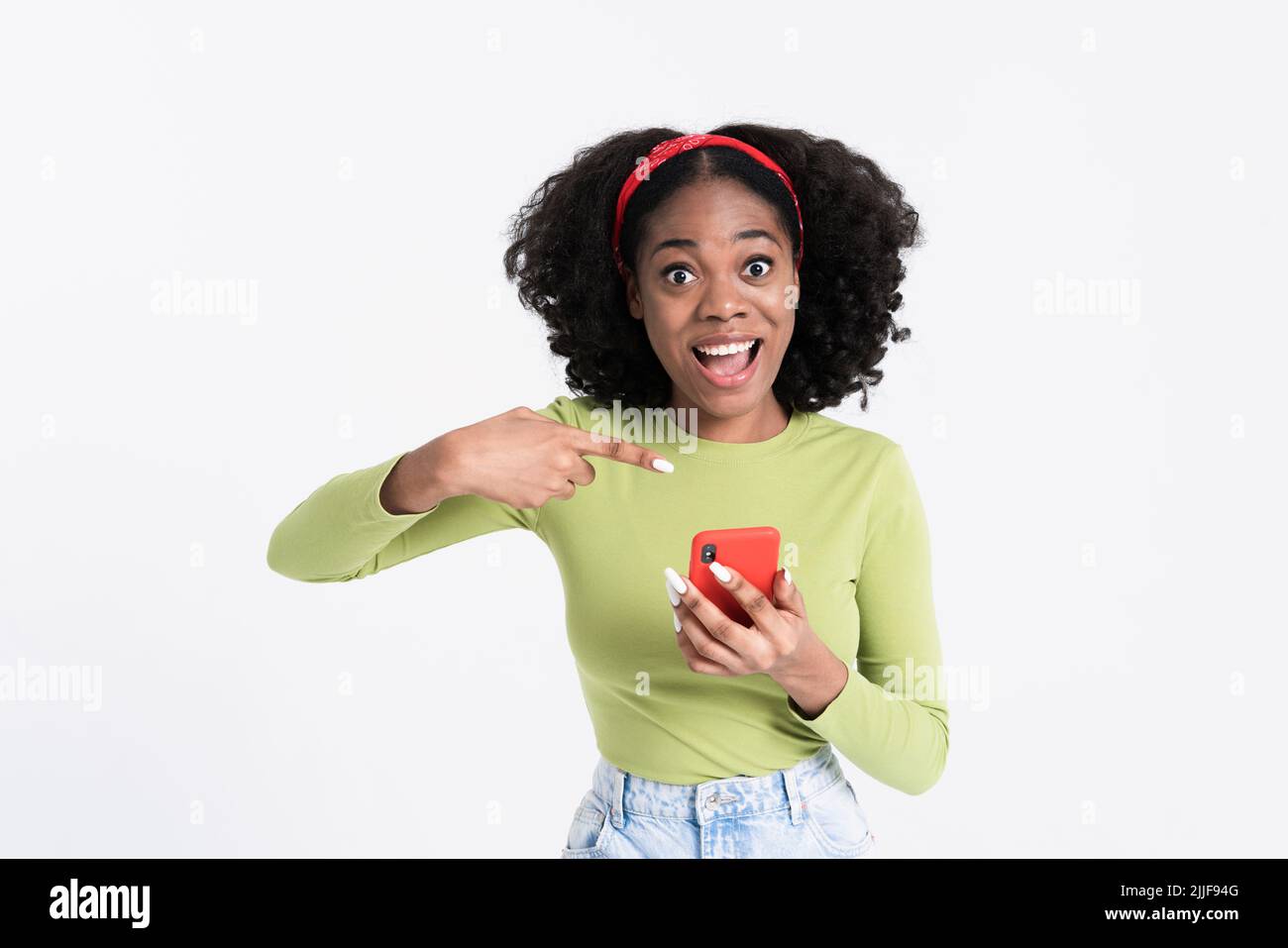Black excited woman pointing finger at her mobile phone isolated over ...