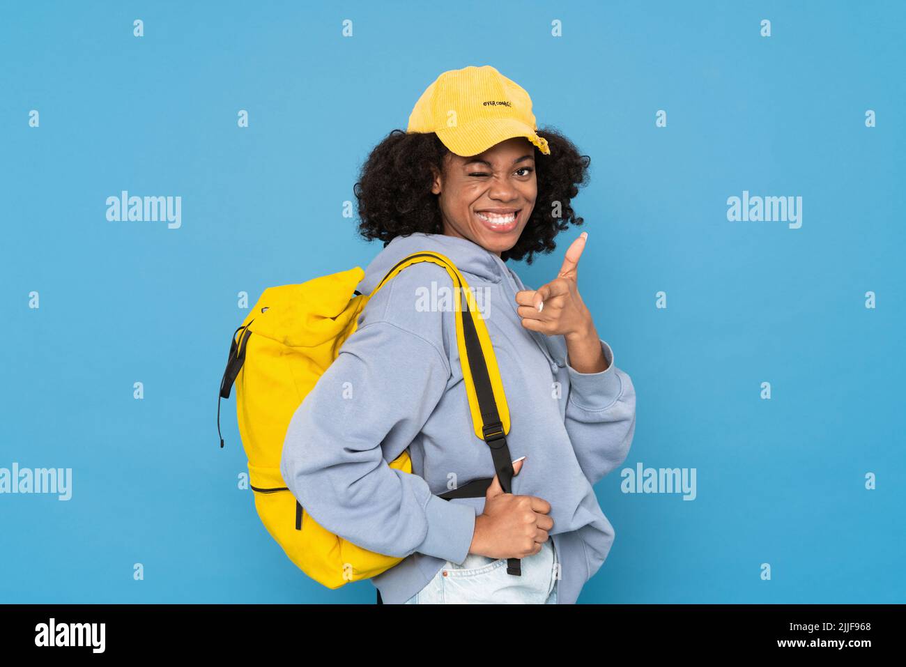 Black woman with backpack winking and pointing finger at camera ...
